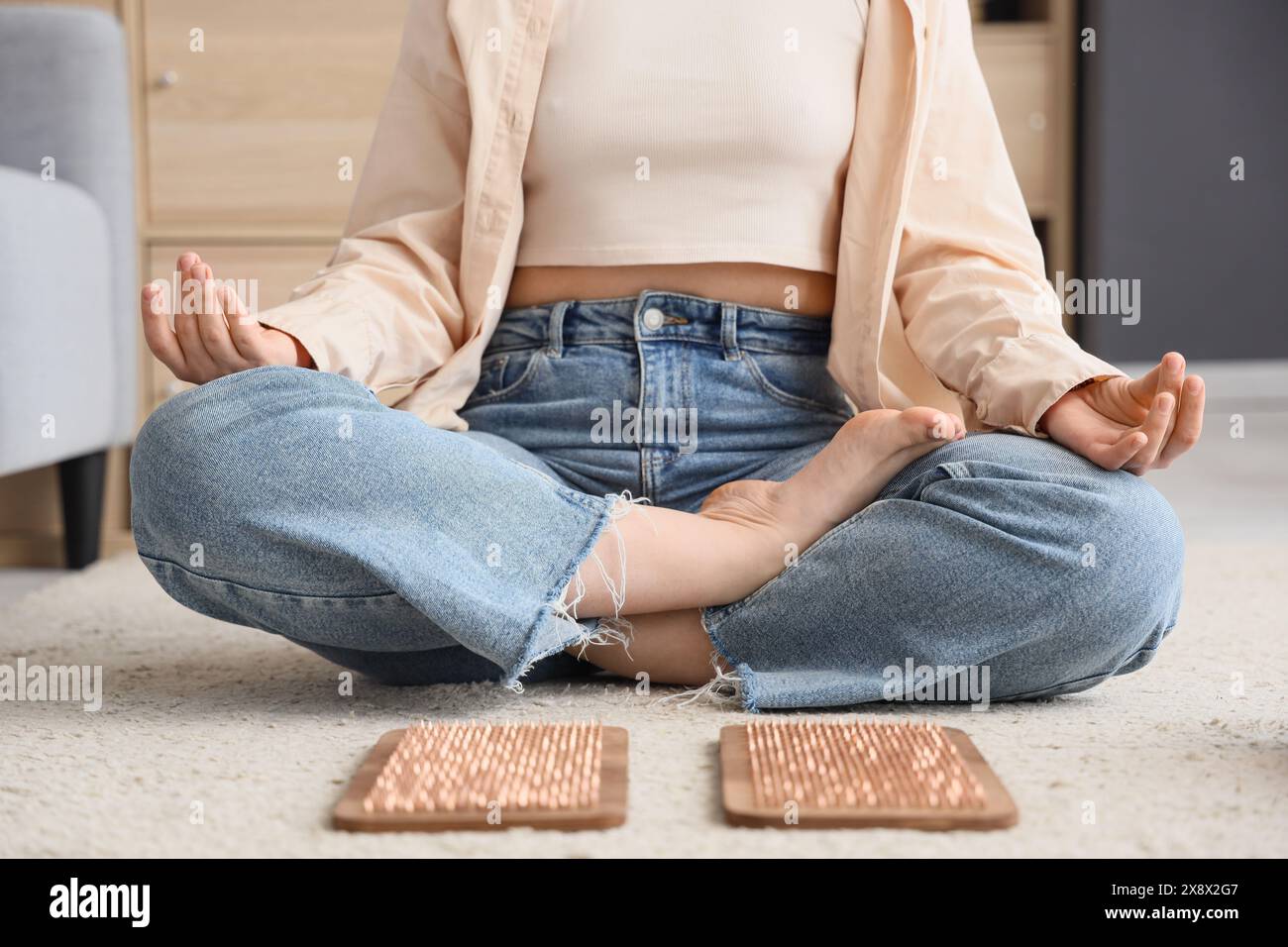 Young woman with Sadhu board meditating on carpet at home, closeup ...
