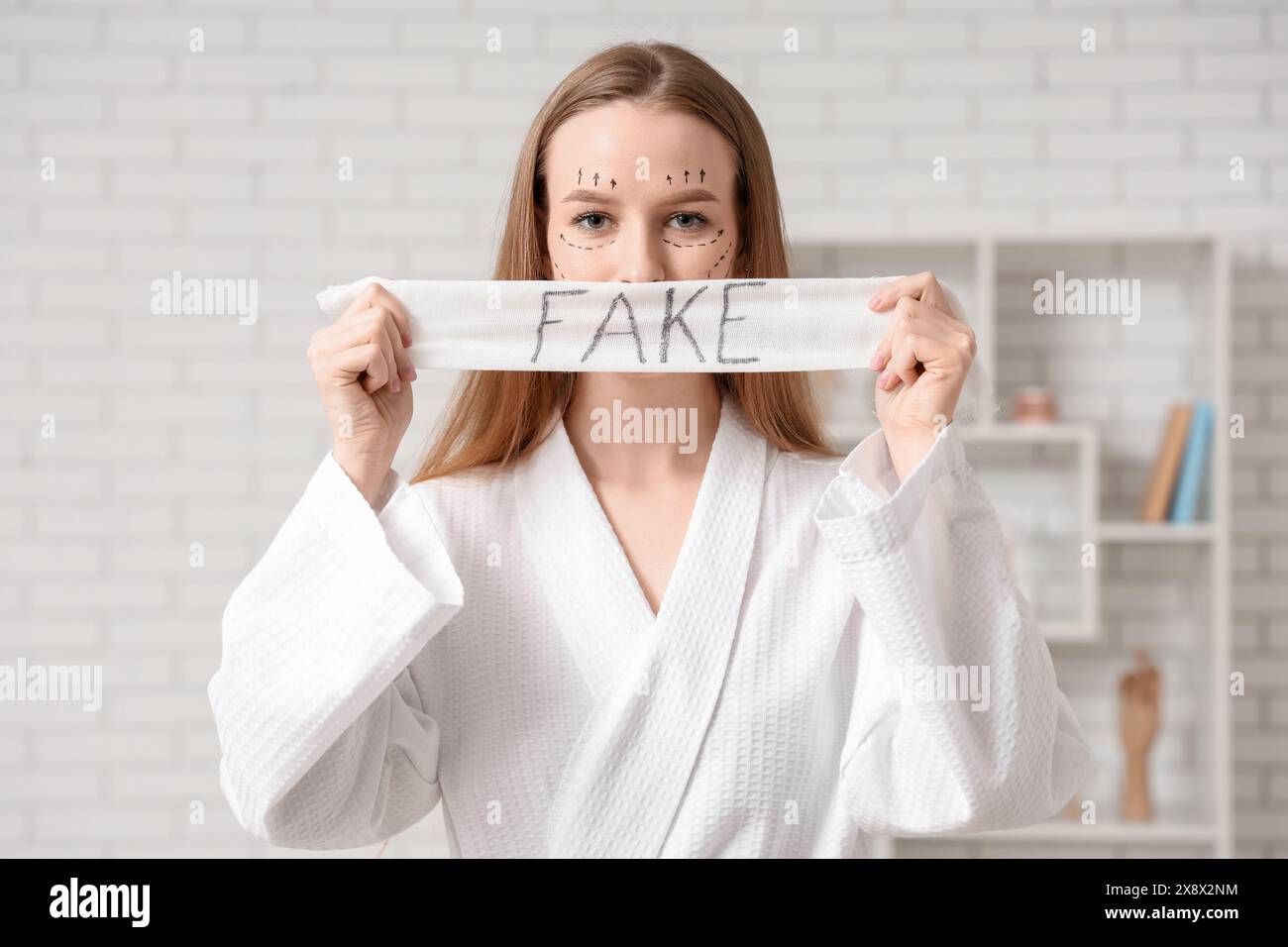 Young woman holding gauze with word FAKE in clinic. Plastic surgery ...