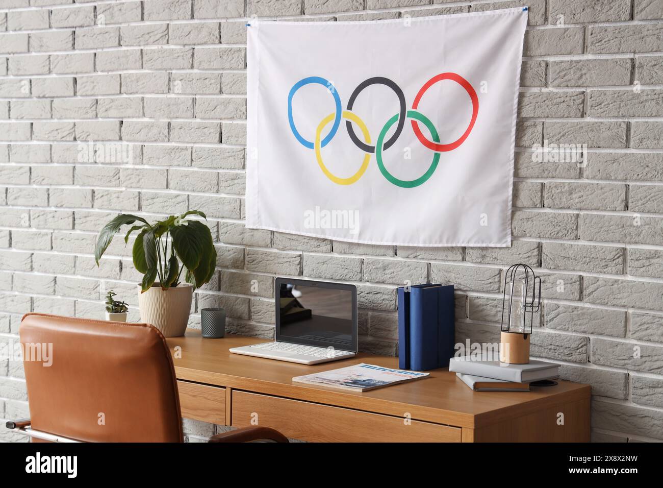 Modern workplace and Olympic flag on grey brick wall in office Stock ...