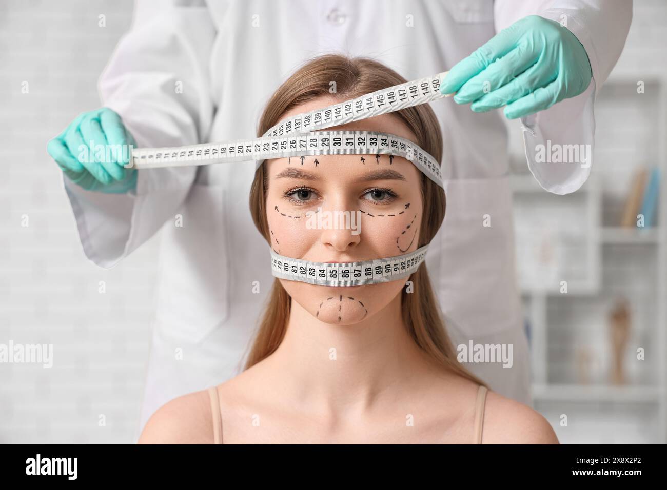 Plastic surgeon with tape measure around woman's head in clinic ...