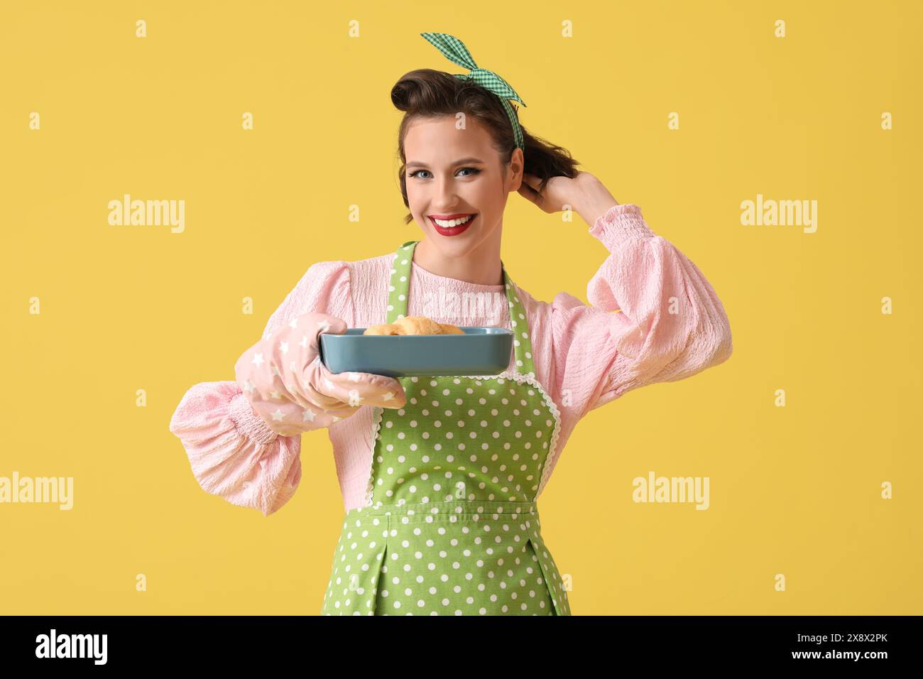 Beautiful young happy pin-up housewife holding baking tray with ...