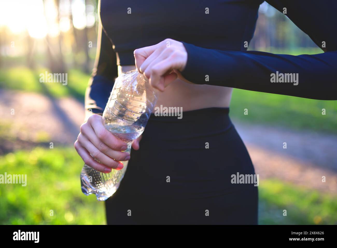 Woman in black sportswear holding a plastic water bottle. Hydration ...