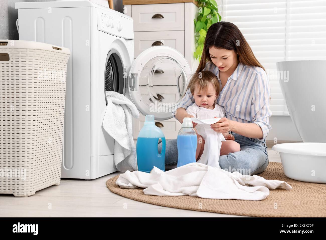 Mother with her daughter washing baby clothes in bathroom Stock Photo ...
