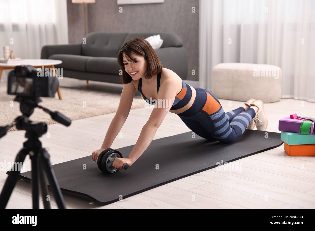 Happy sports blogger training with ab roller while recording fitness ...