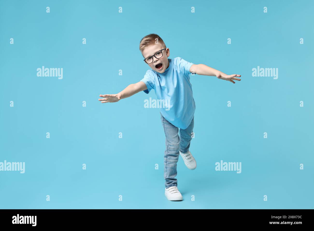Happy little boy dancing on light blue background Stock Photo - Alamy