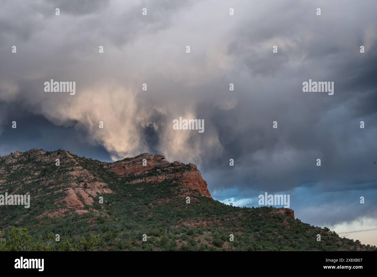 Storm clouds reflect sunlight over red rocks formation near Sedona ...