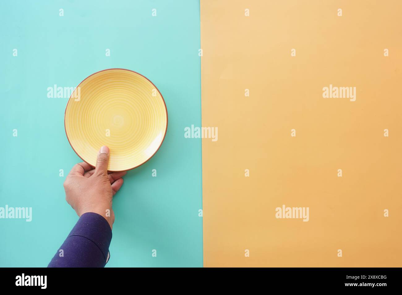 Hand Holding Yellow Plate on Split Color Background Stock Photo - Alamy