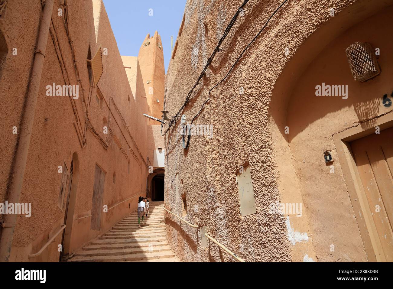 Narrow street with the minaret of the great mosque of Ghardaia in the ...