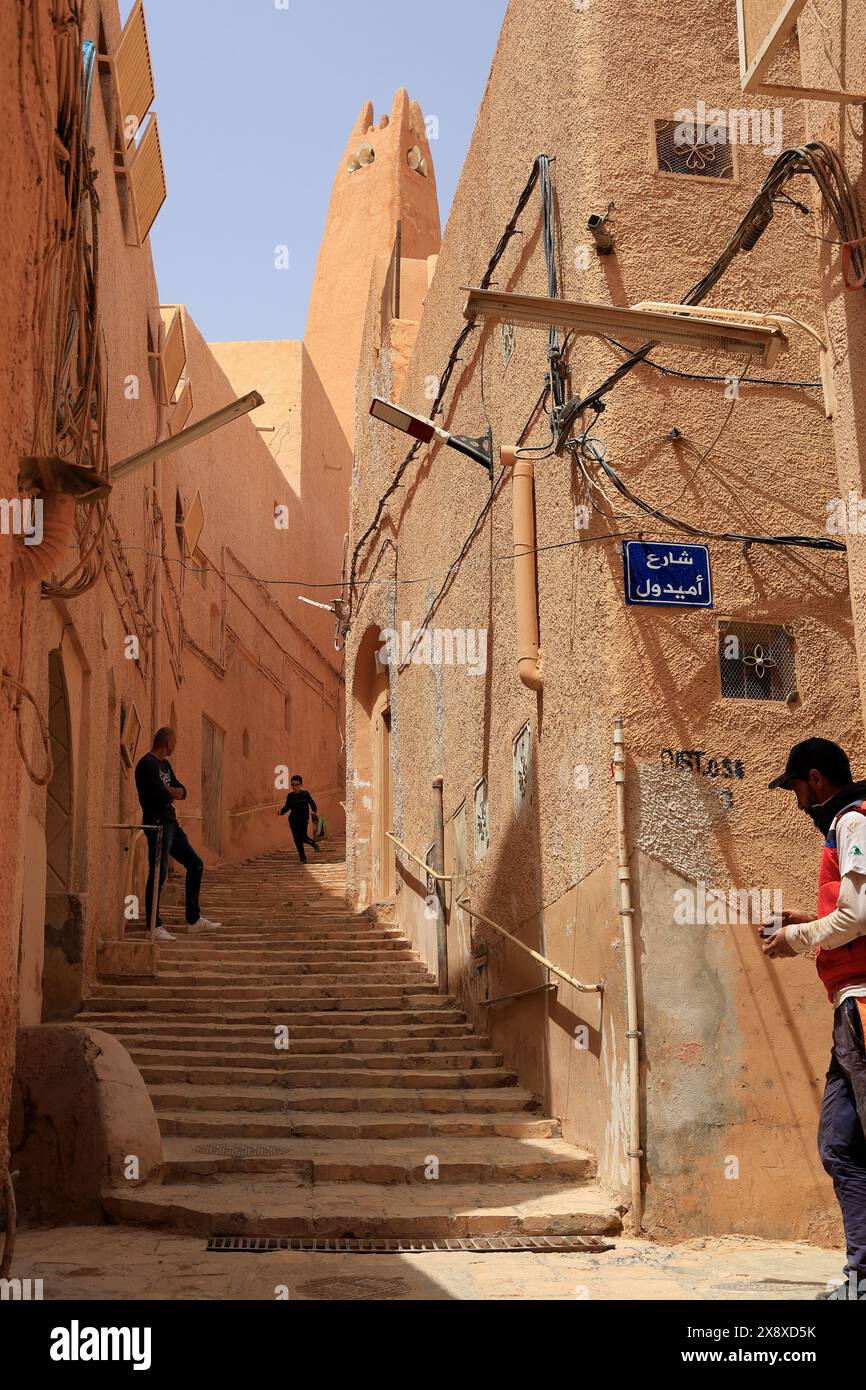 Narrow street with the minaret of the great mosque of Ghardaia in the ...