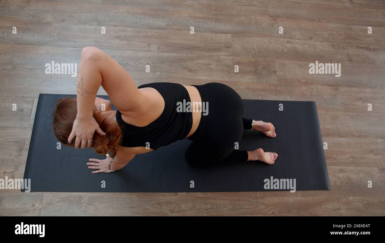A woman from a knee elbow position making the bends of the body. Media ...