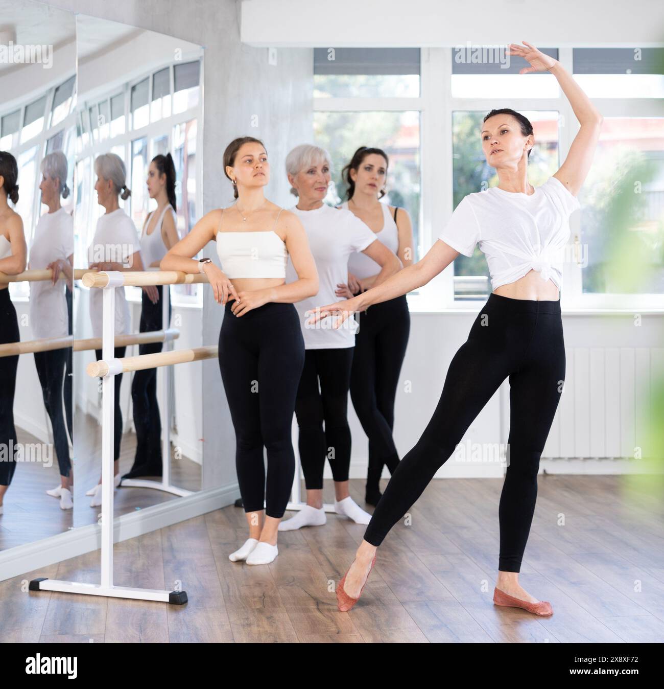 Female teacher leading ballet class, showing movements to group Stock ...