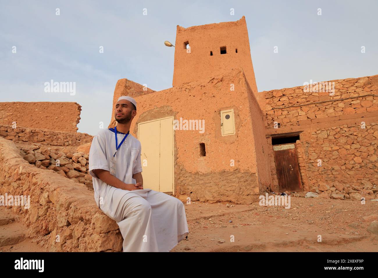 A man in traditional outfit in front of the grand mosque of Ksar ...
