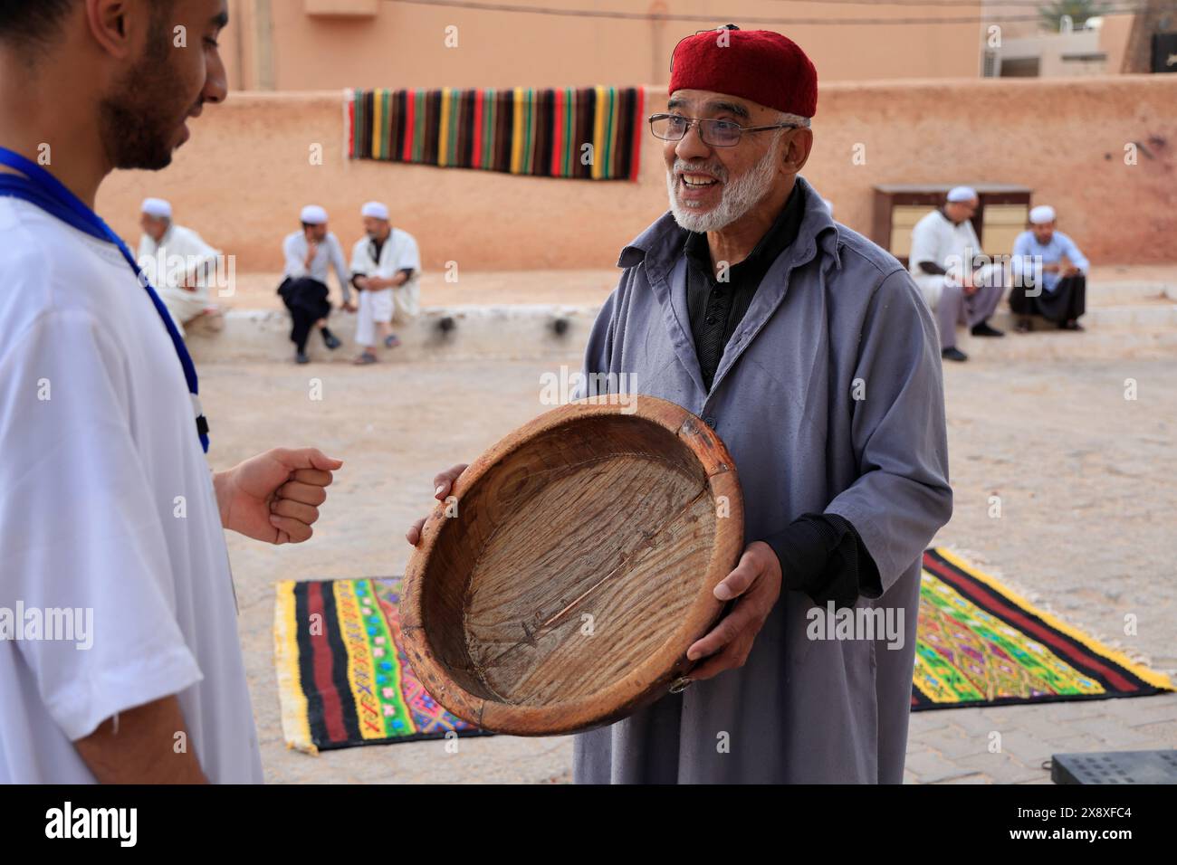 A Mozabite men showing a wooden tray for auction in a traditional ...