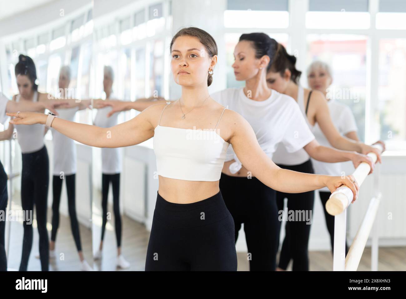 Graceful women of different ages practice at ballet stand in fifth ...