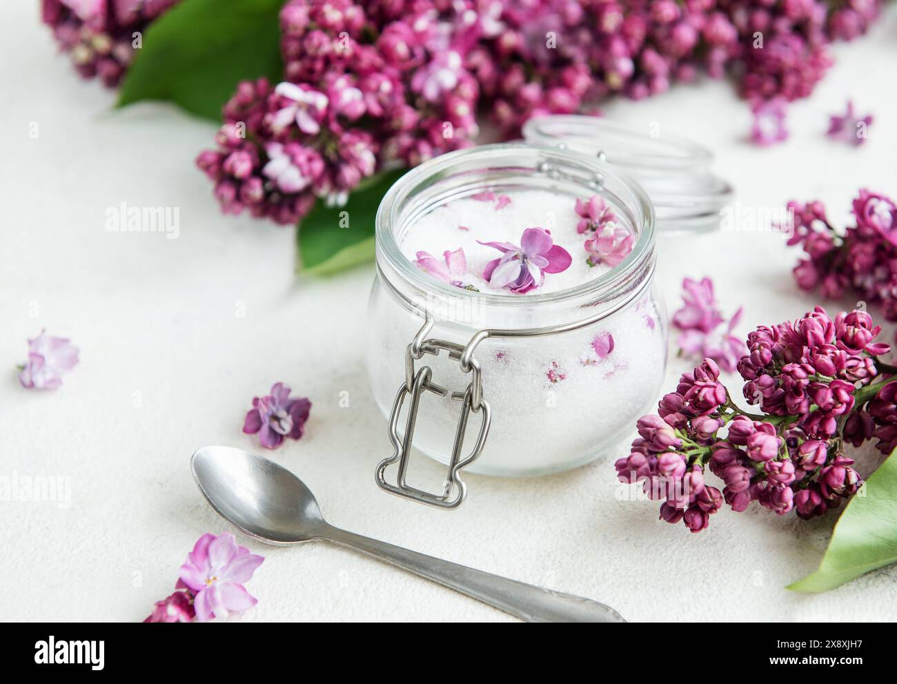 A clear glass jar with a silver clasp is filled with homemade lilac ...
