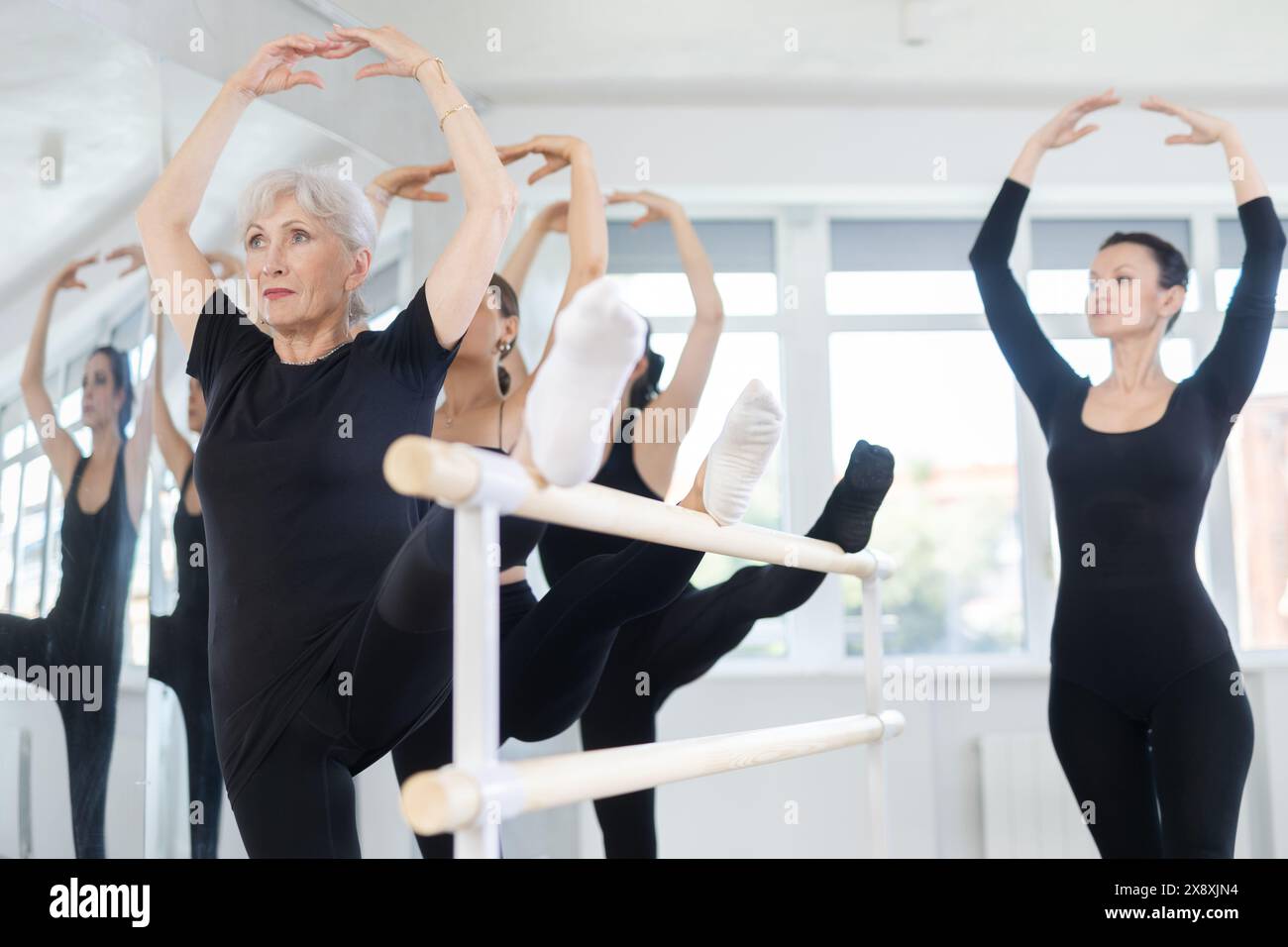 Elderly woman mastering developpe at barre in ballet class Stock Photo ...
