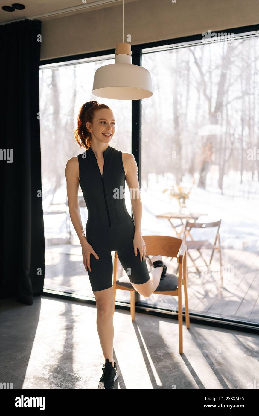Vertical portrait of fit slim female doing single leg lunge using chair ...