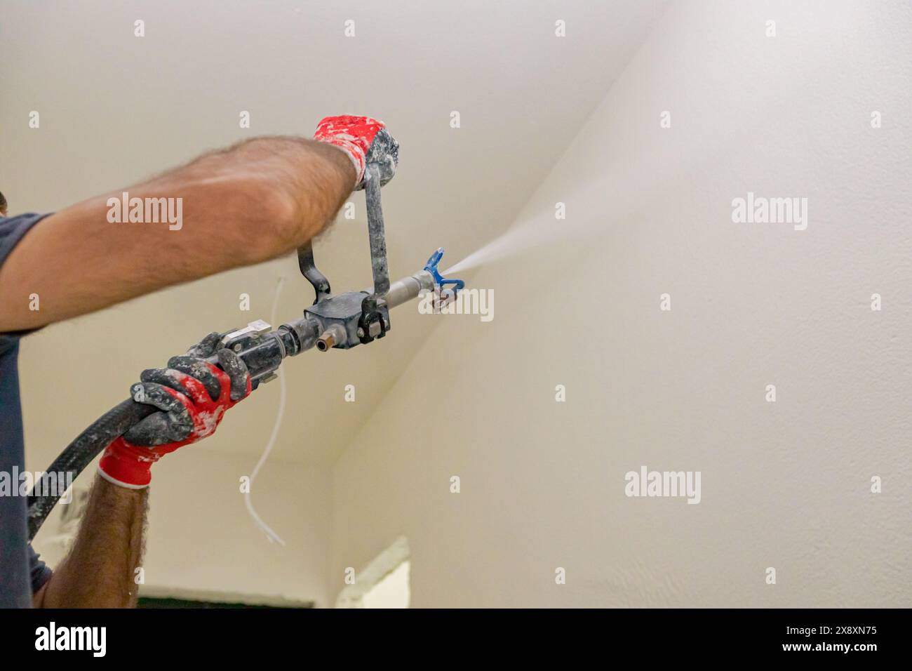 Construction worker applies a white coat, putty on the wall, using ...