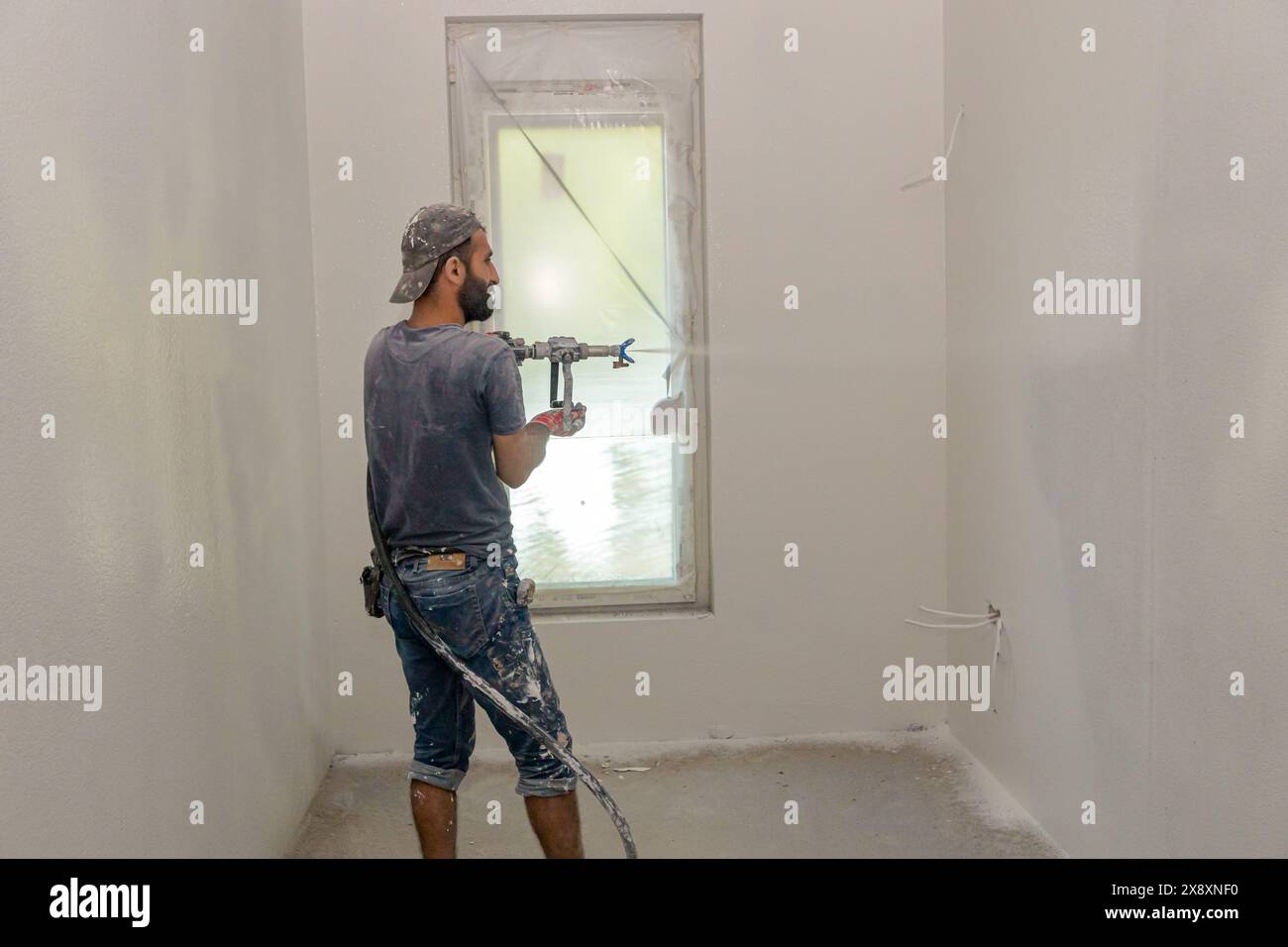 Construction worker applies a white coat, putty on the wall, using ...