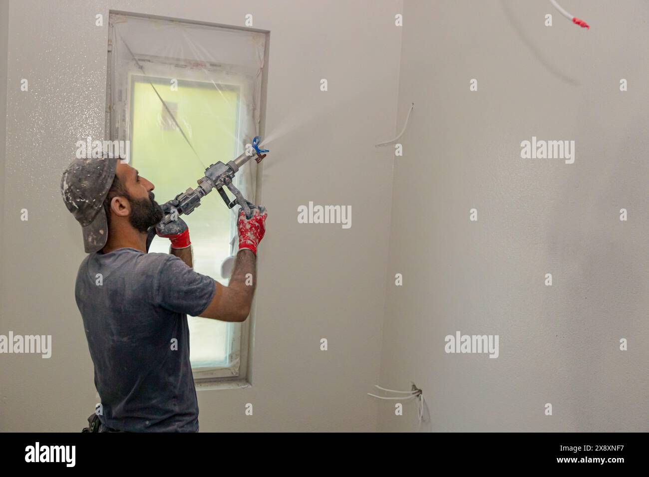 Construction worker applies a white coat, putty on the wall, using ...
