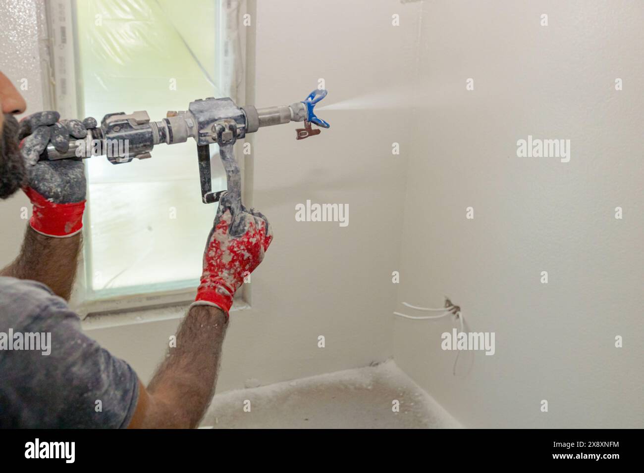 Construction worker applies a white coat, putty on the wall, using ...