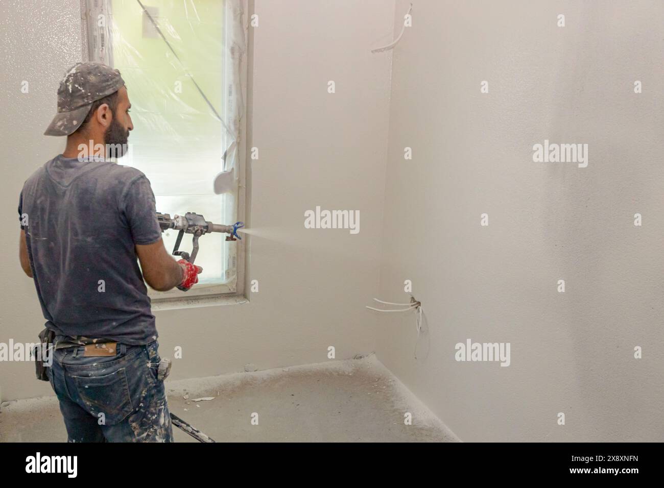 Construction worker applies a white coat, putty on the wall, using ...