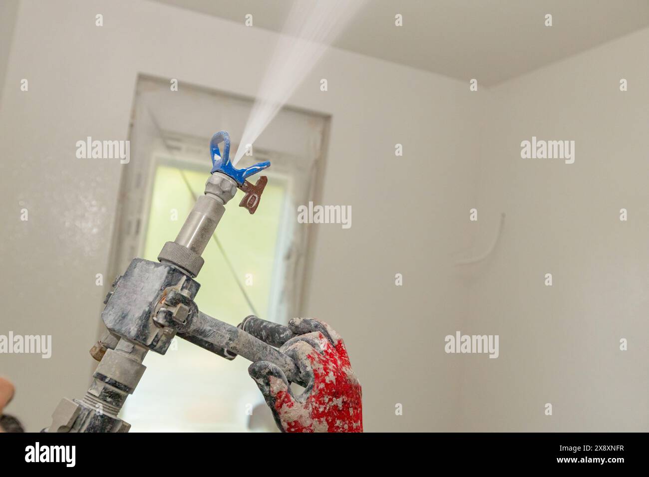 Construction worker applies a white coat, putty on the wall, using ...