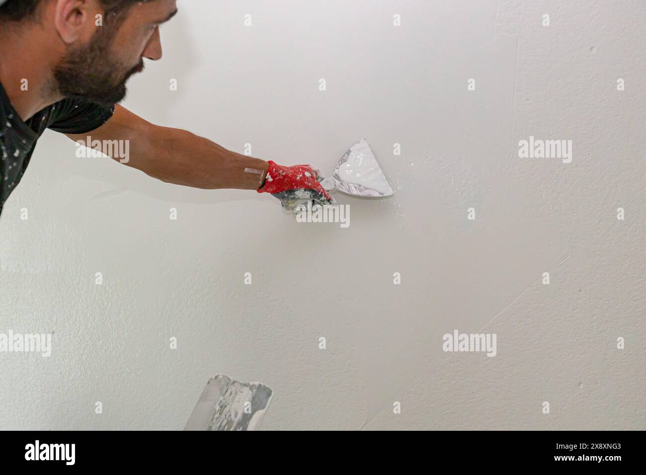 Hand with a spatula. Worker is fixing wall surface as applying skim ...