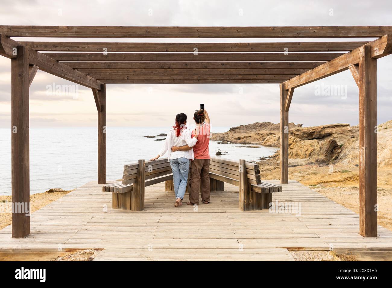 Couple on beach calling on phone taking selfie on wooden porch at ...