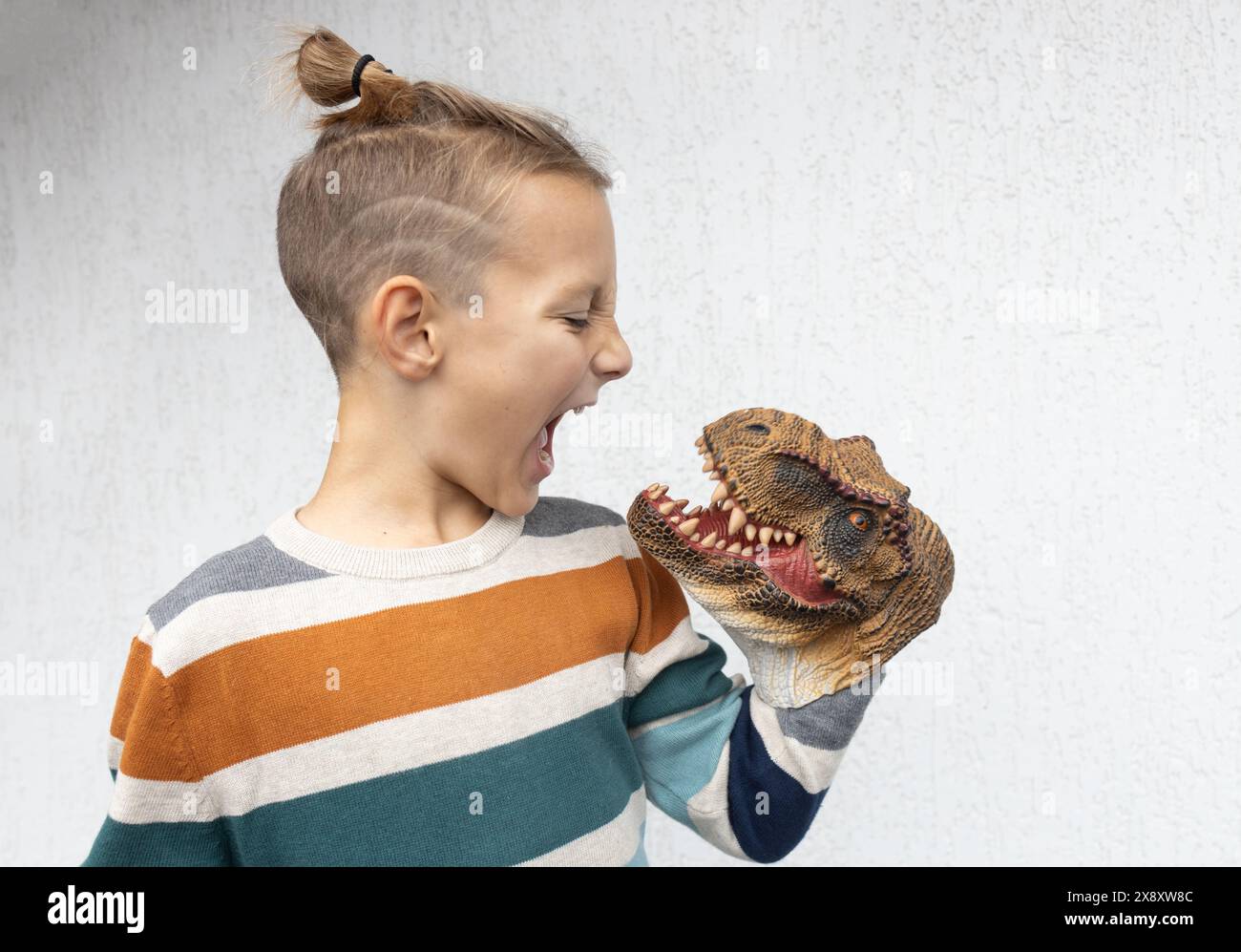 child plays with scary toy head of dinosaur, putting it on hand ...