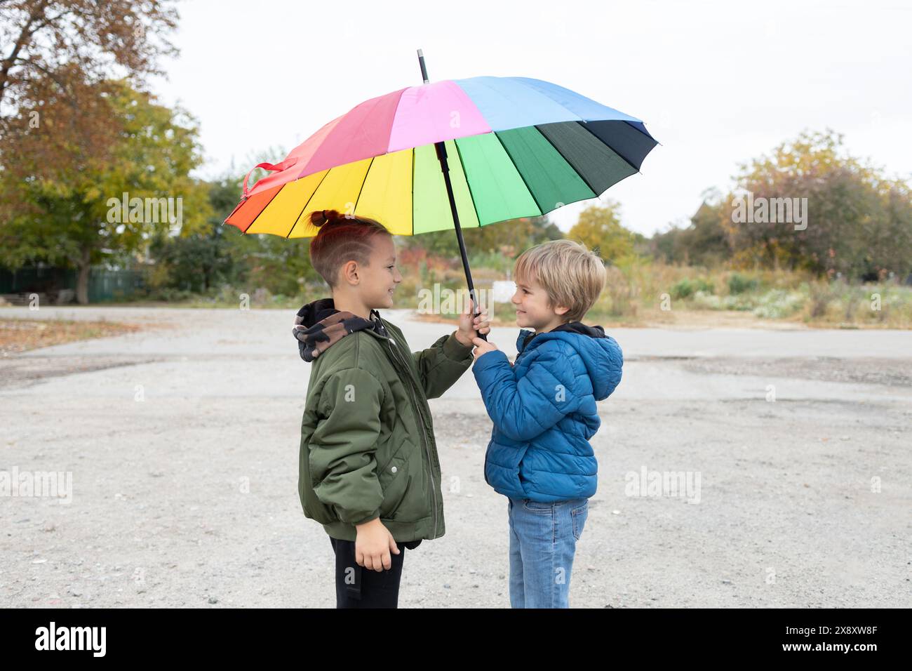two children, boys 7 years old, stand together under a large rainbow ...