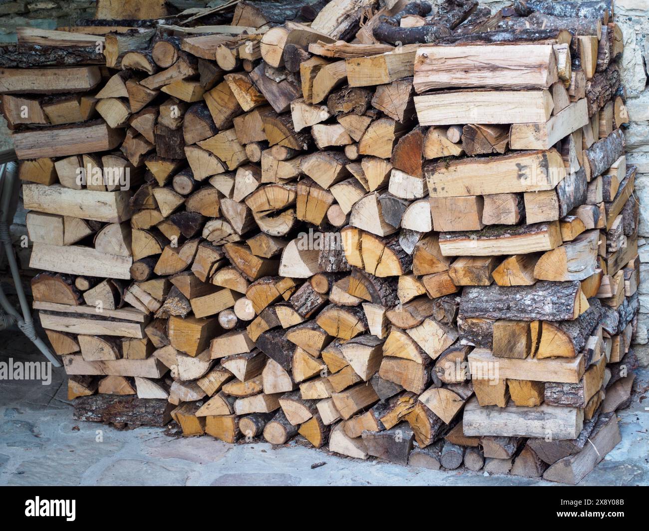 Neatly organized stack of chopped hardwood firewood against a rustic ...