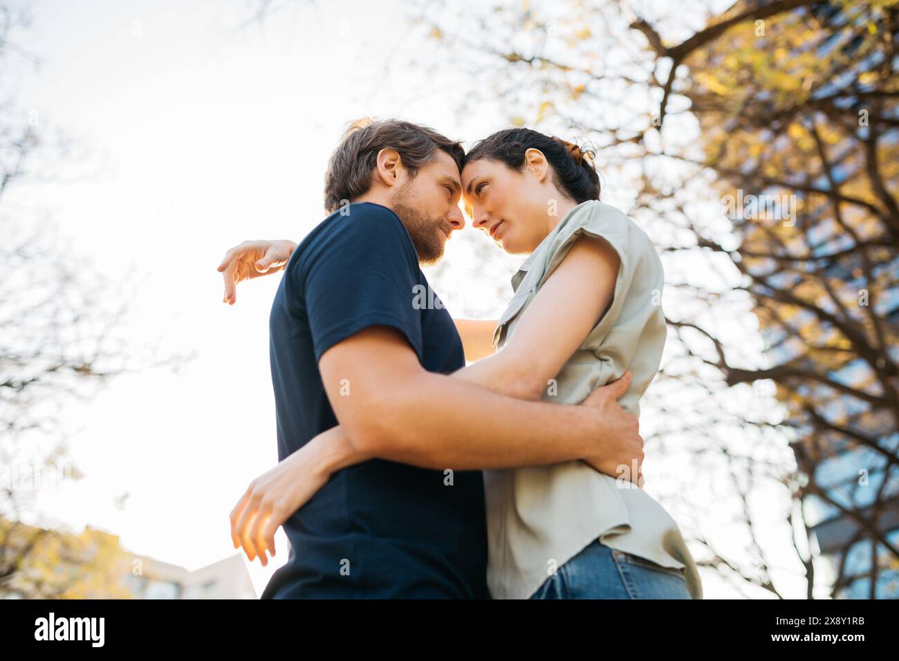 Couple embraces closely, foreheads touching, in an intimate moment ...