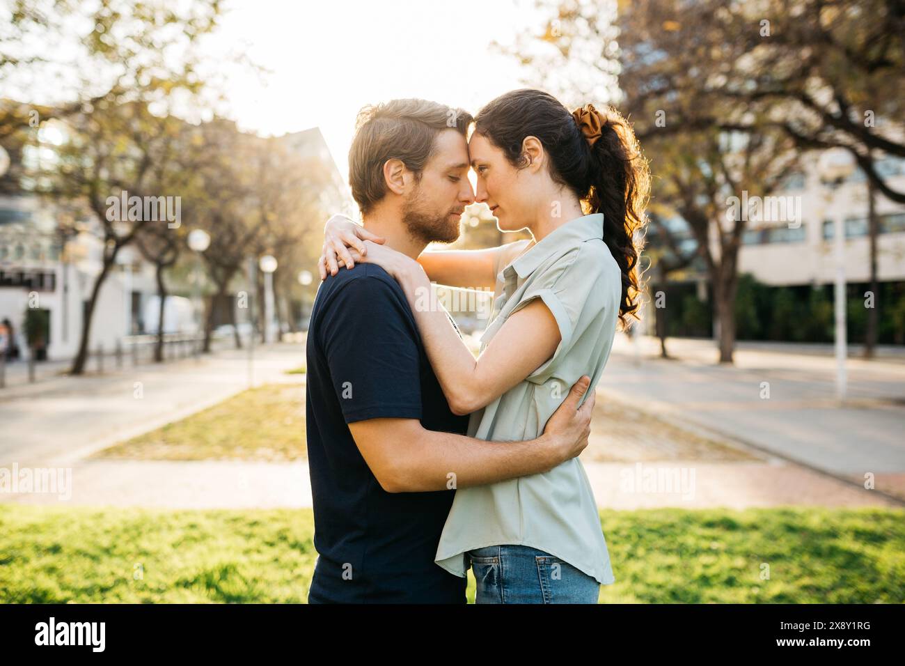 Couple embraces closely, foreheads touching, in an intimate moment ...