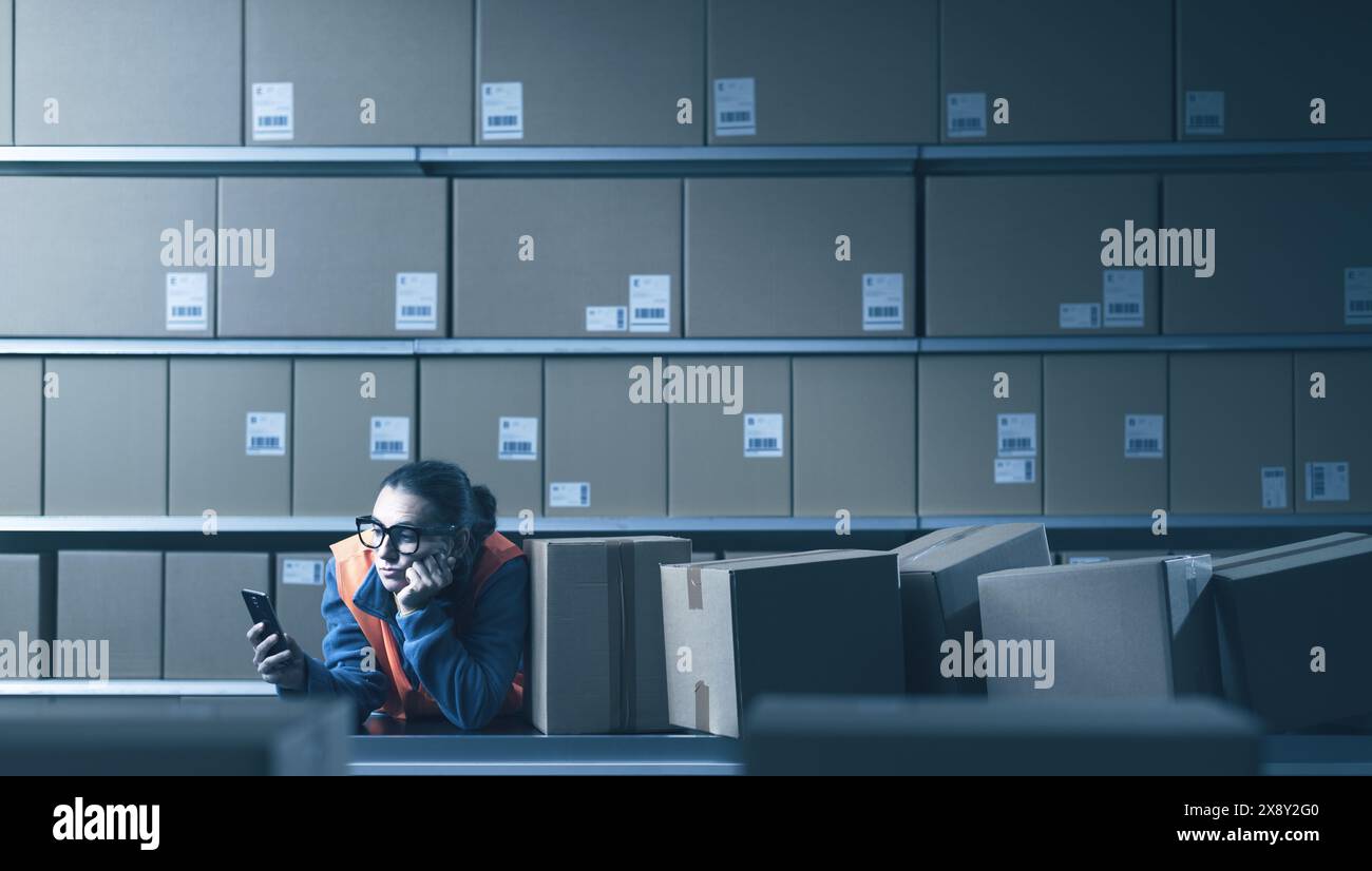 Distracted careless warehouse worker using her smartphone, the boxes ...