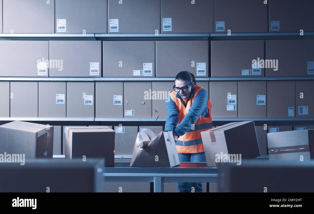 Angry aggressive warehouse worker hitting cardboard boxes with a bat ...