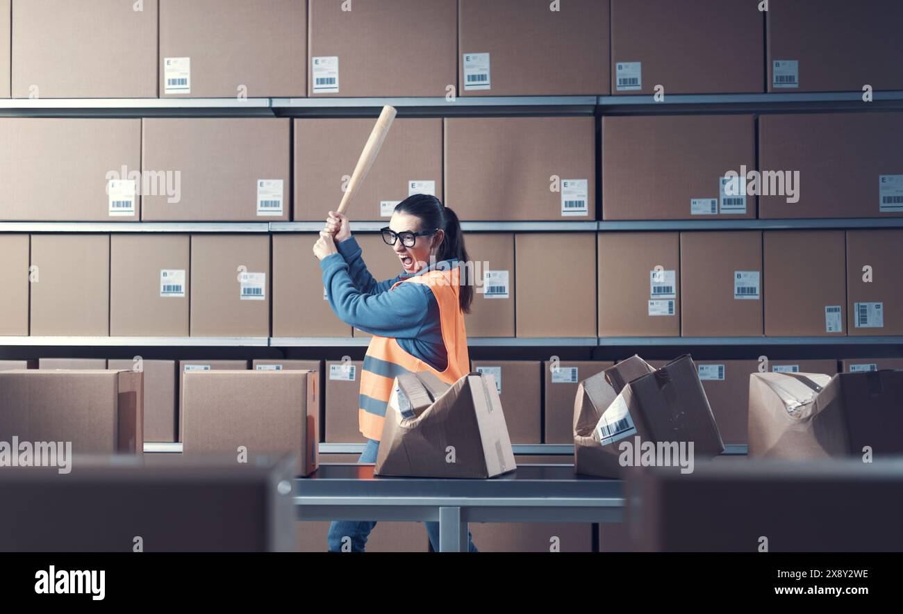 Angry aggressive warehouse worker hitting cardboard boxes with a bat ...