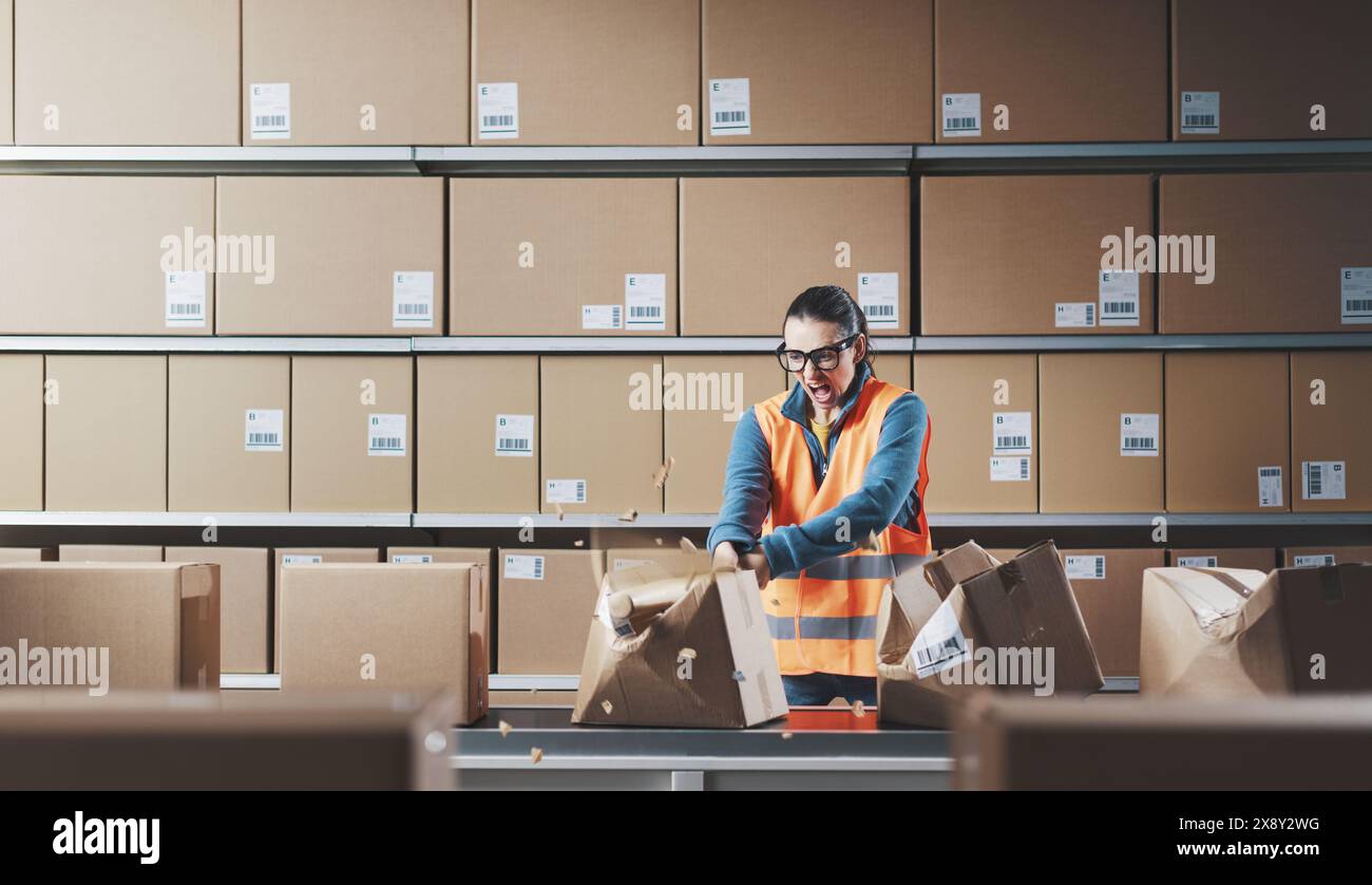 Angry aggressive warehouse worker hitting cardboard boxes with a bat ...