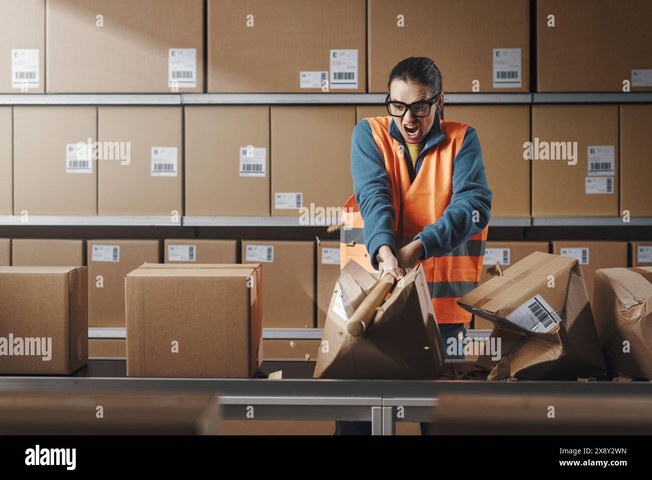 Aggressive rebellious warehouse worker smashing boxes at work, she is ...