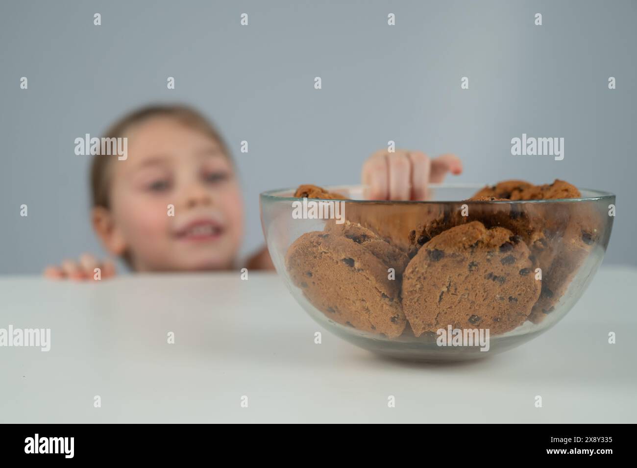 Little girl steals cookies from the table Stock Photo - Alamy