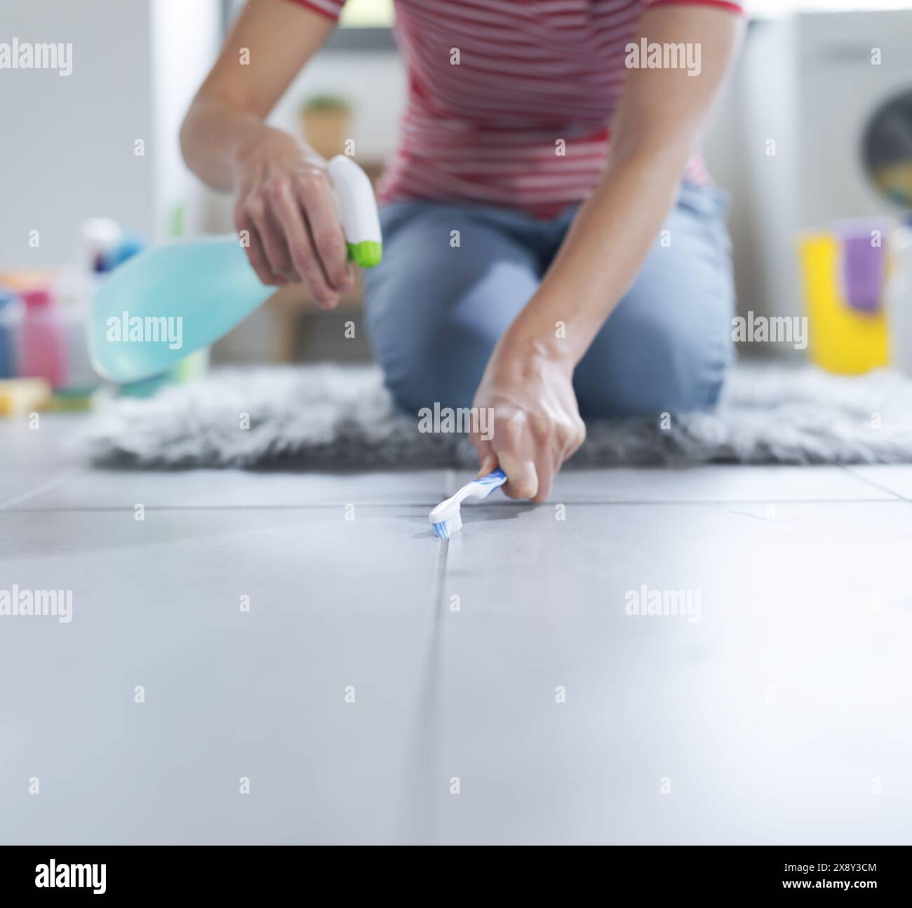Careful woman cleaning the bathroom floor, she is scrubbing the joints ...