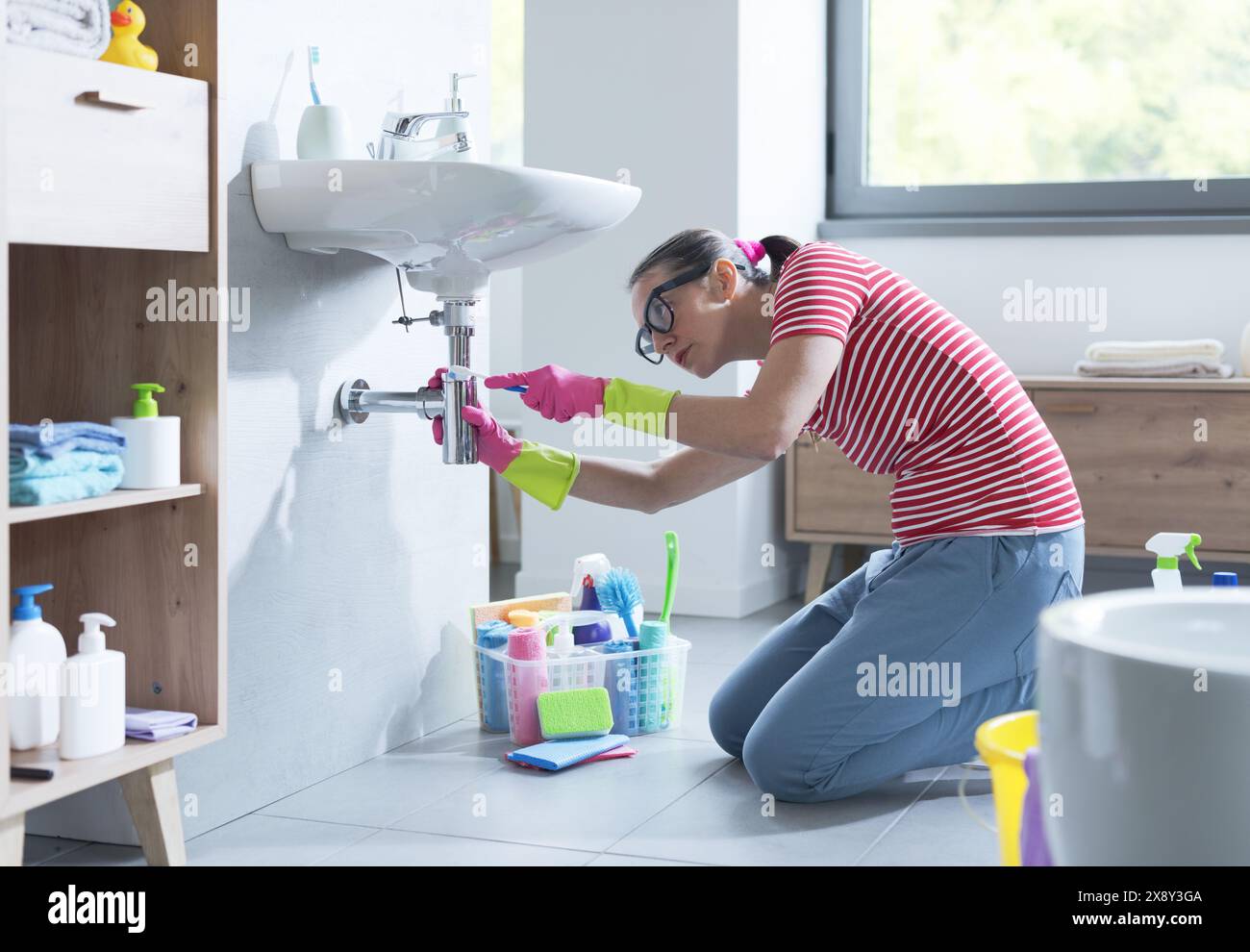 Efficient housewife doing chores, she is cleaning the bathroom sink ...