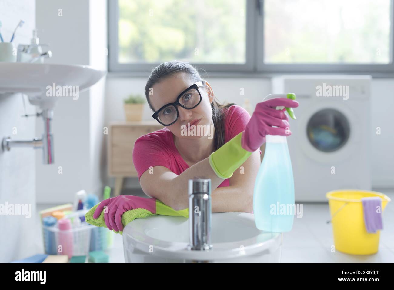 Bored frustrated woman doing chores, she is cleaning the bathroom with ...
