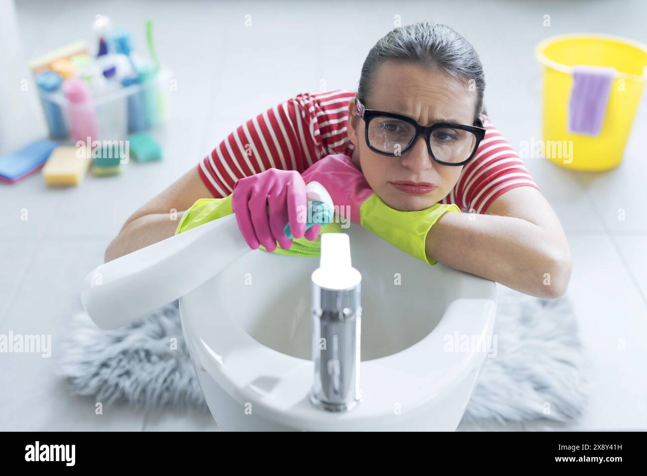 Bored frustrated woman doing chores, she is cleaning the bathroom with ...
