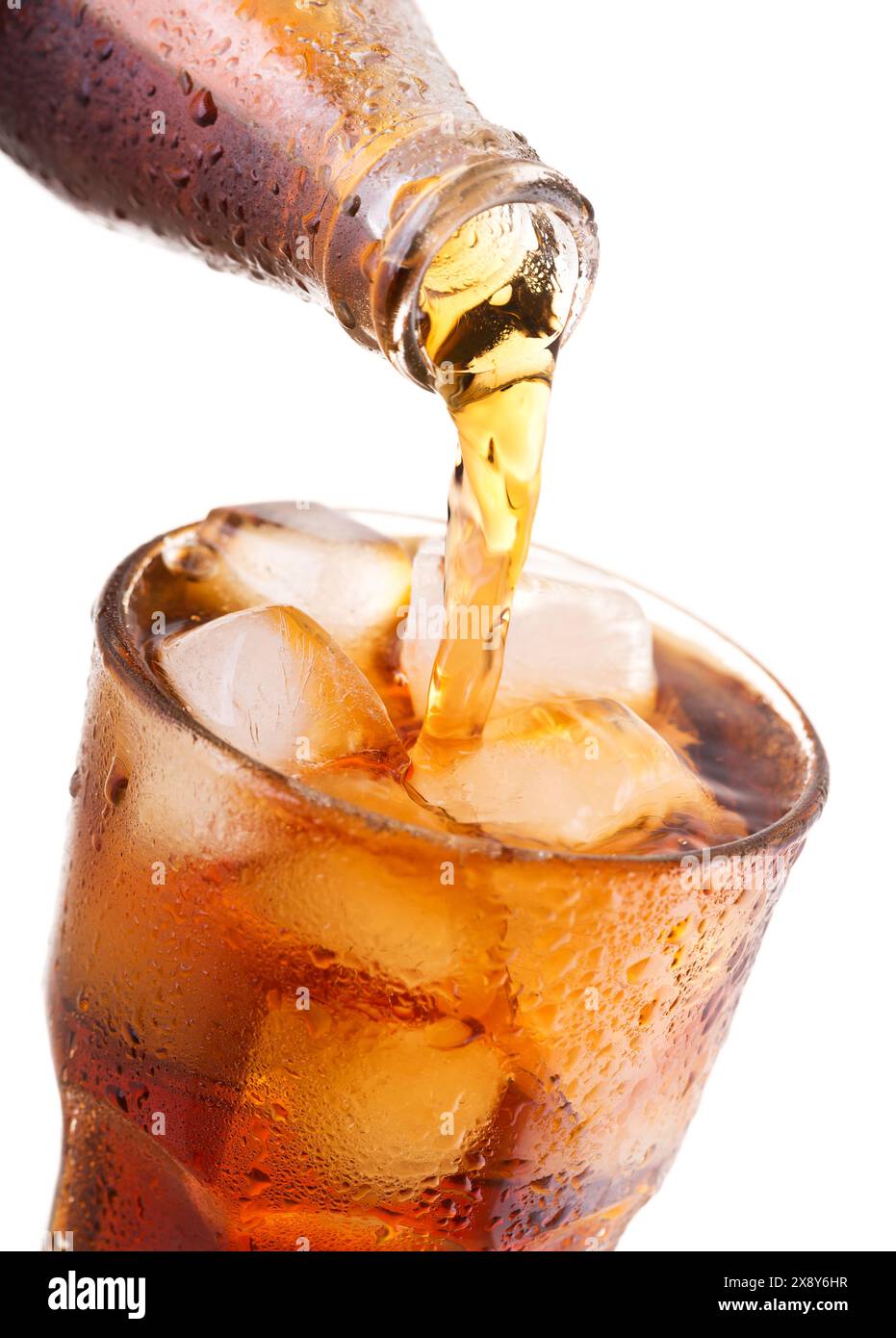 pouring cola into glass with ice from bottle isolated on white ...