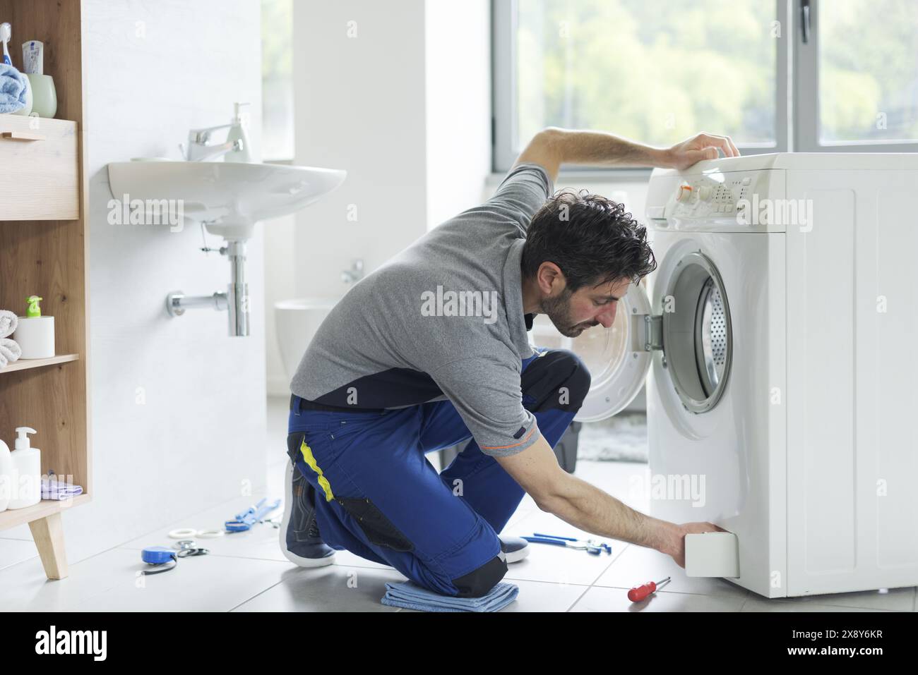 Plumber repairing a clogged washing machine, he is checking the drain ...