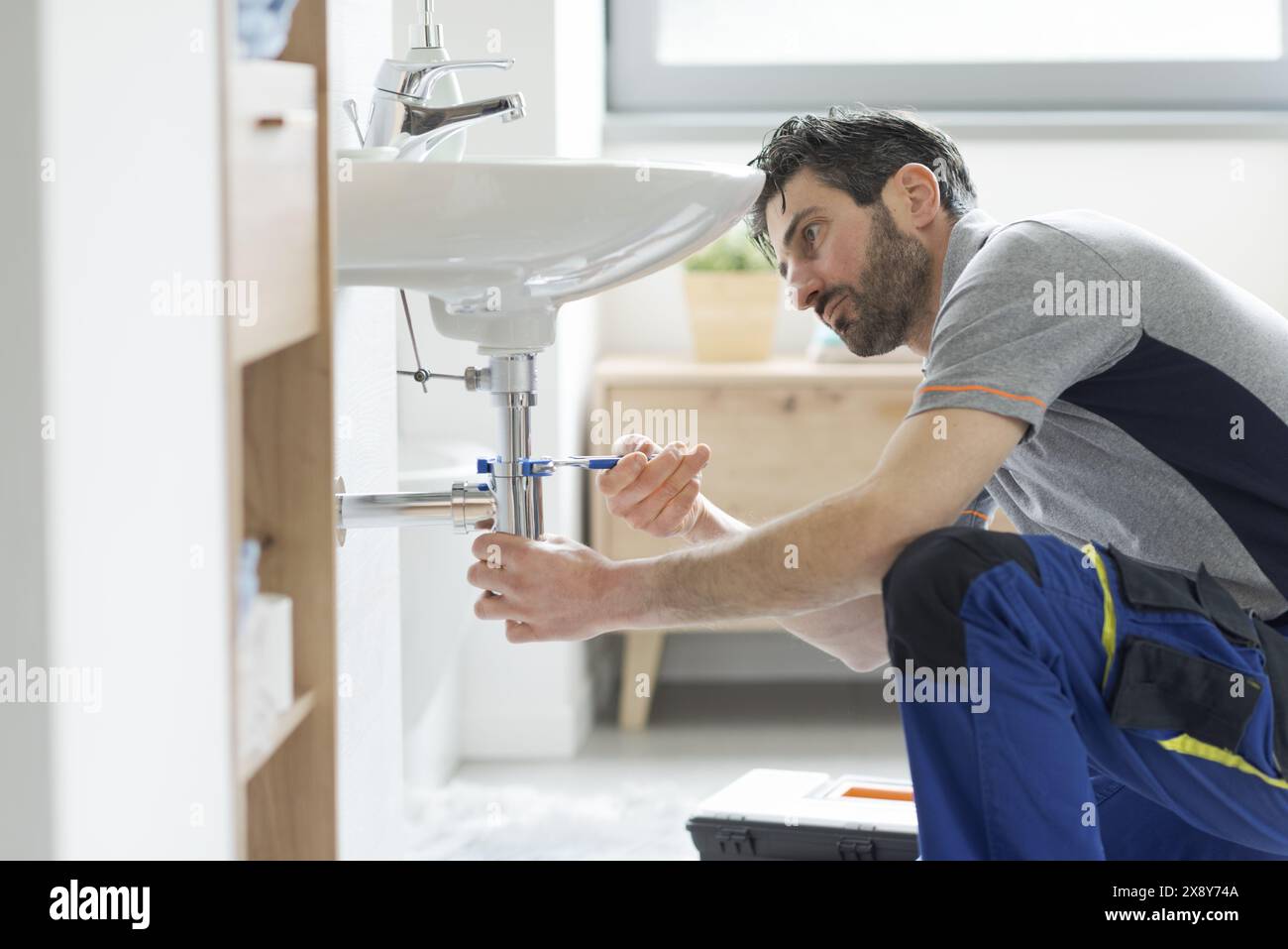 Professional plumber fixing a bathroom sink using water pump pliers ...