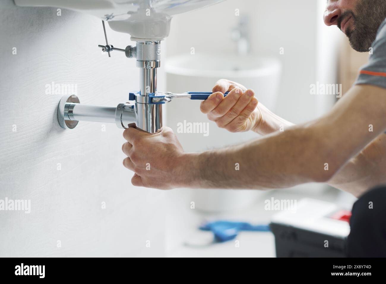 Professional plumber fixing a bathroom sink drain using water pump ...