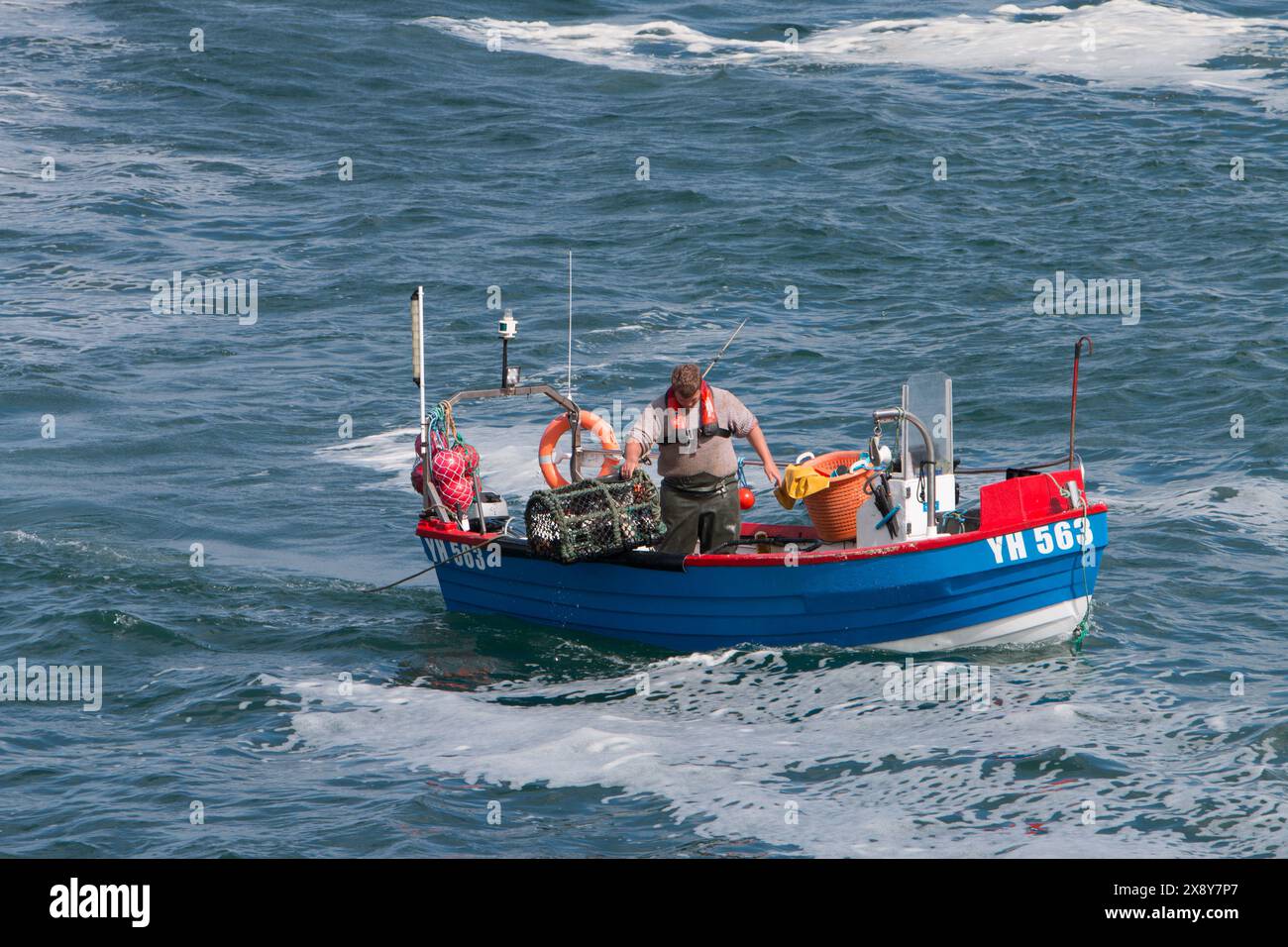Small open boat with single fisherman setting and pick up crab pots ...