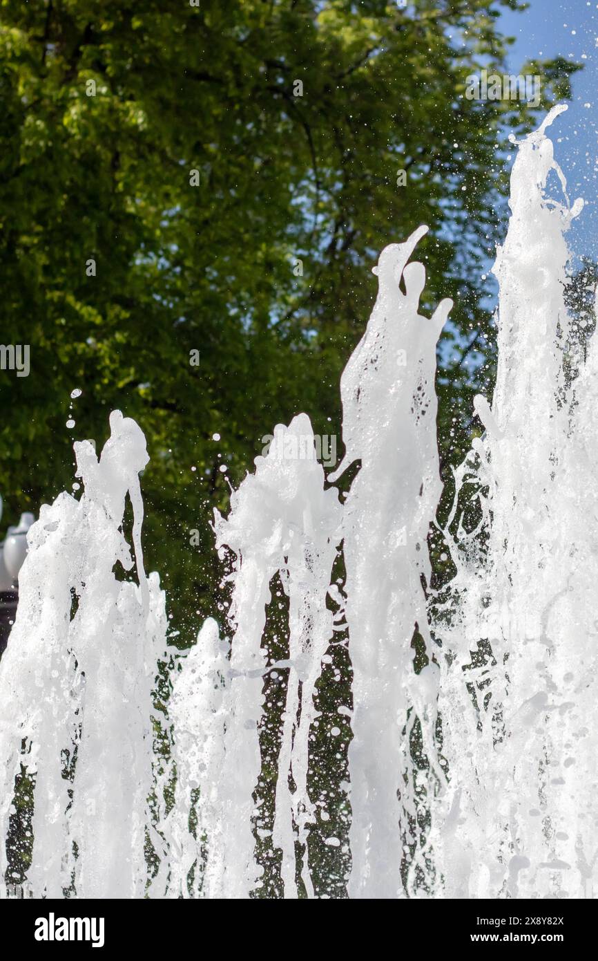 A fountain in a park with trees in the background, the flowing water ...